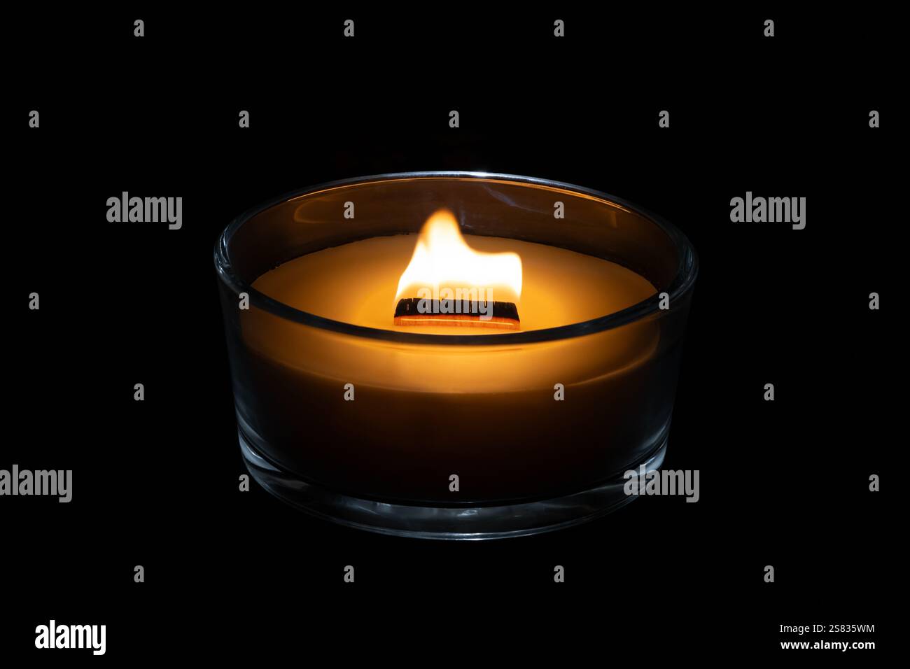 Burning candle in glass holder on o black background, complete candle ...
