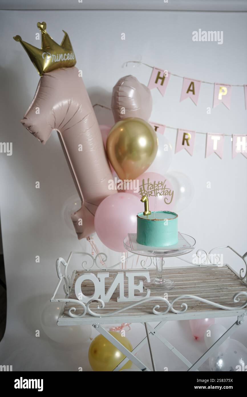 A first birthday celebration setup featuring a teal birthday cake with ...