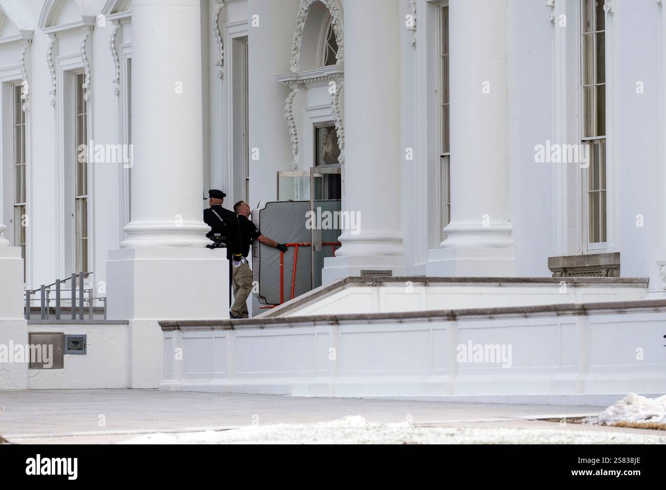 A worker hauls a mattress out the front doors of the North Portico at ...
