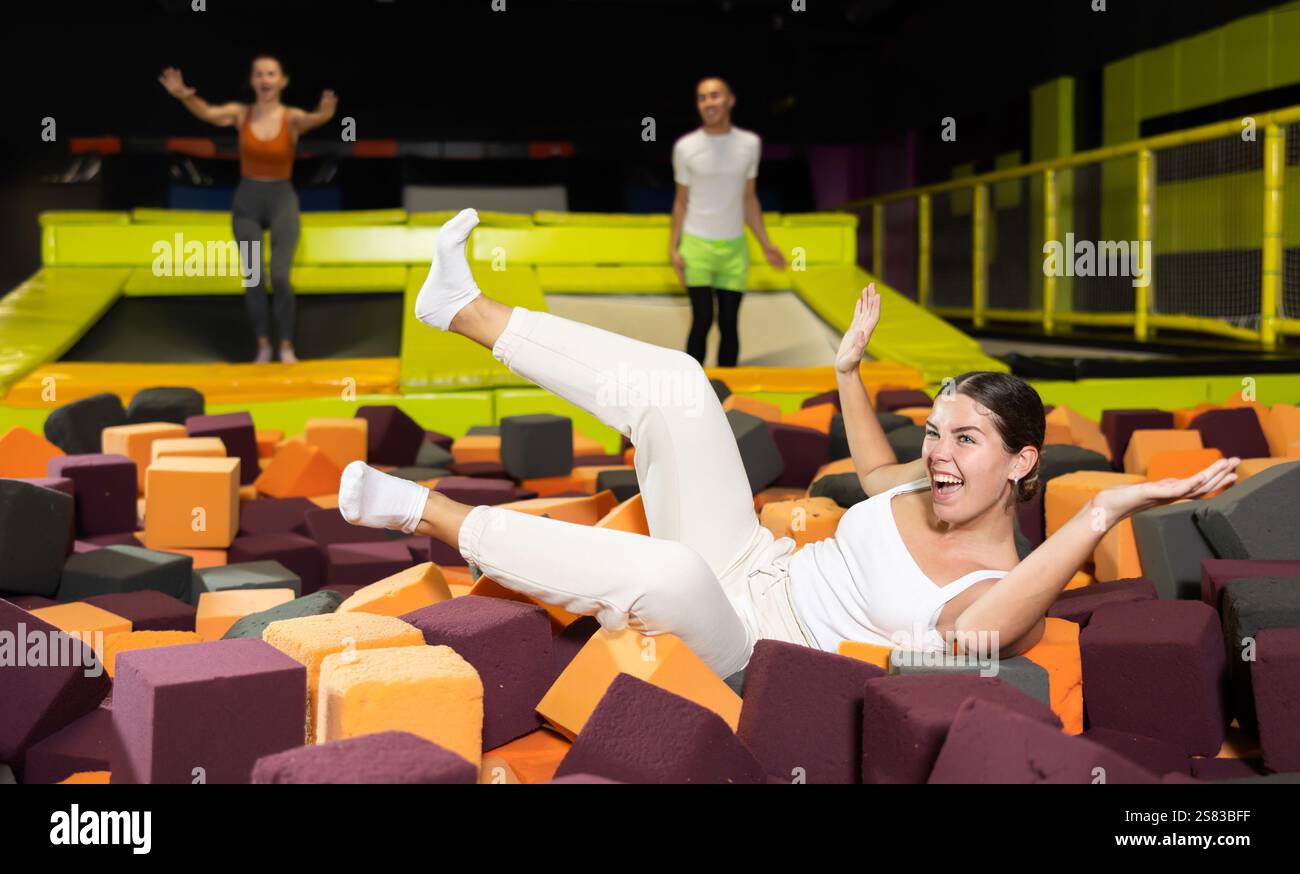 Joyful girl jumping into foam pit at indoor trampoline arena Stock ...