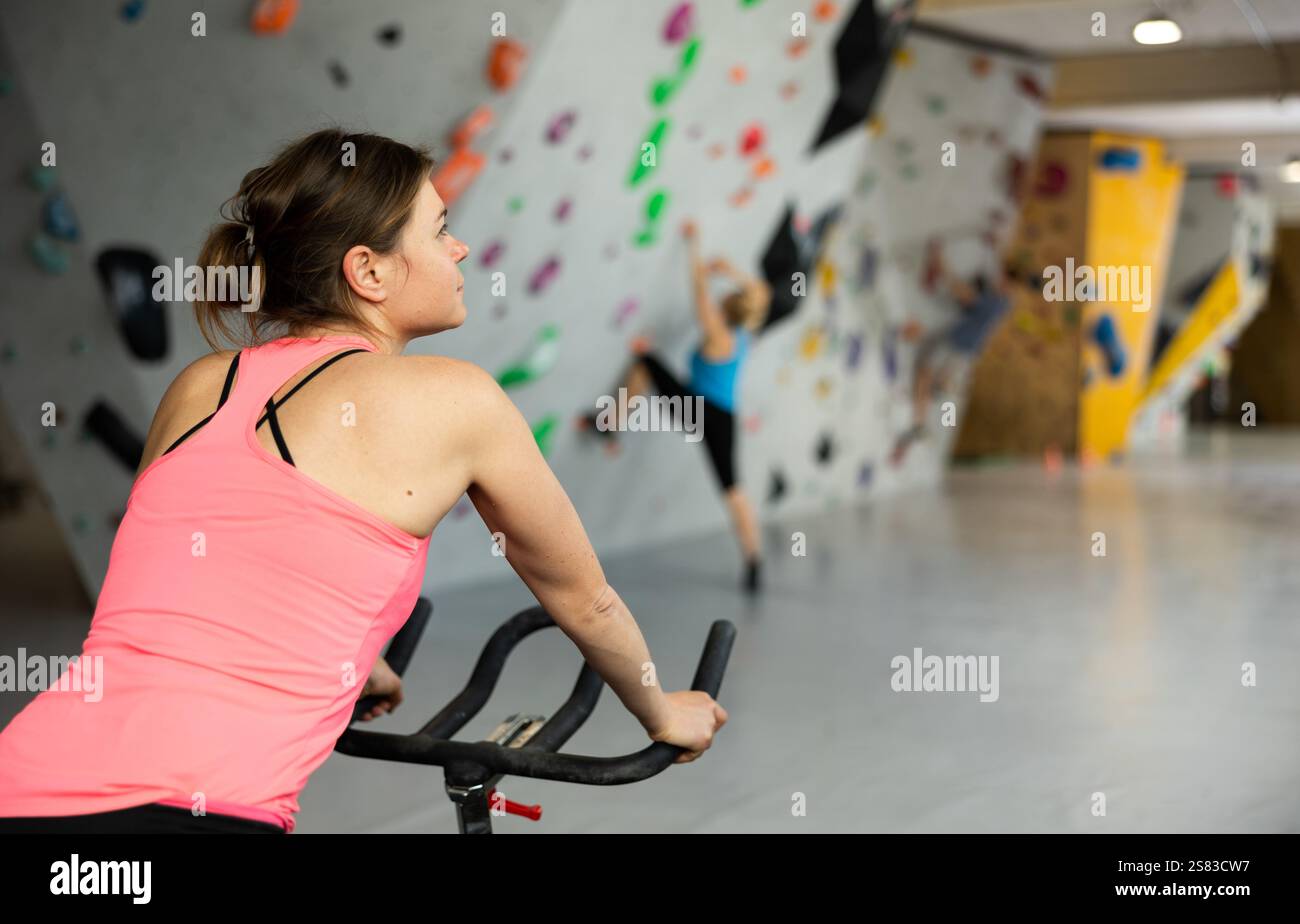 Sports girl on an exercise bike in climbing hall Stock Photo - Alamy