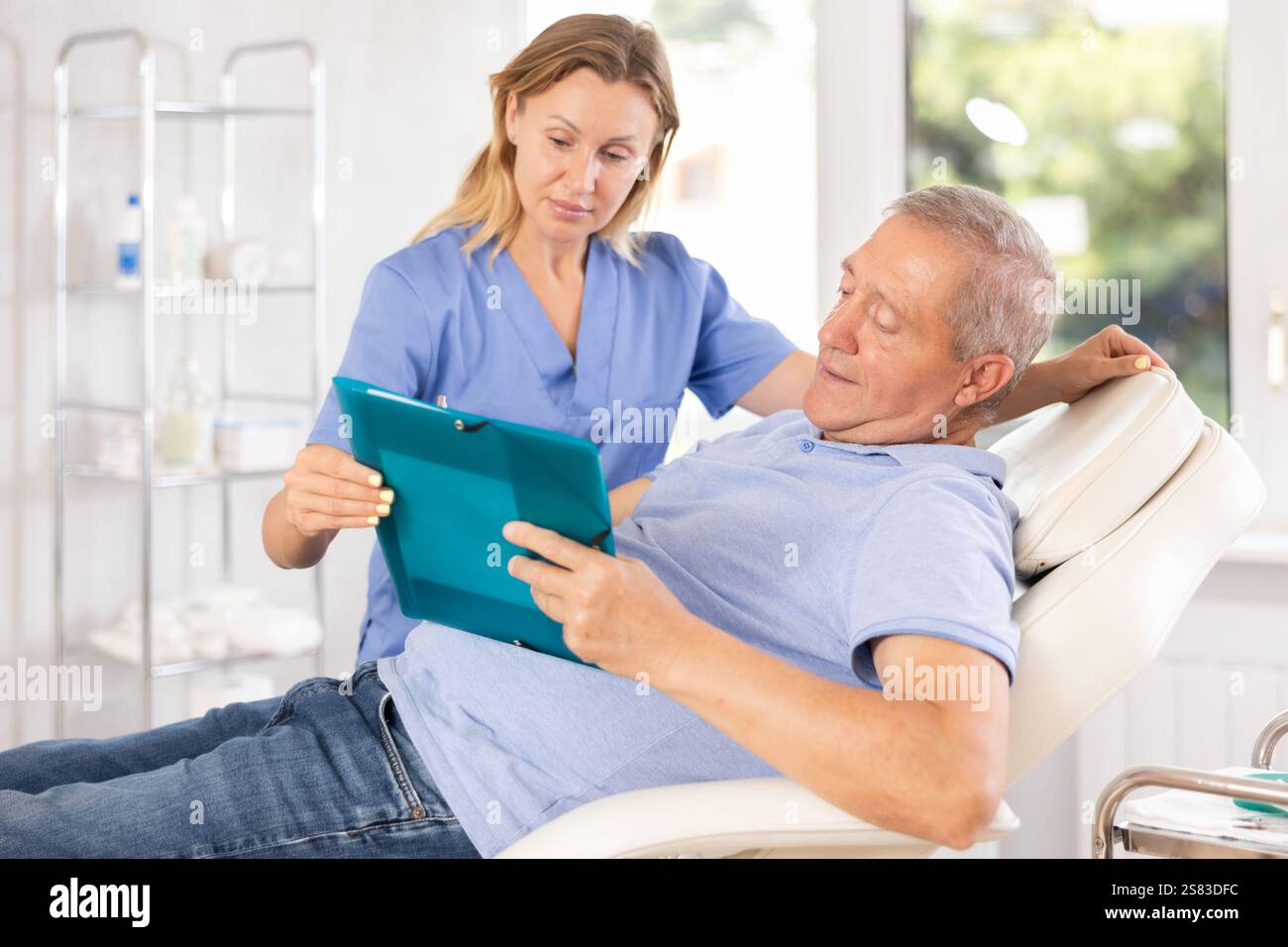 Old male patient signing papers while talking with woman doctor Stock ...