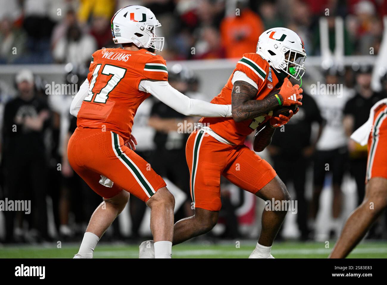 Miami quarterback Emory Williams (17) hands off to running back Mark ...
