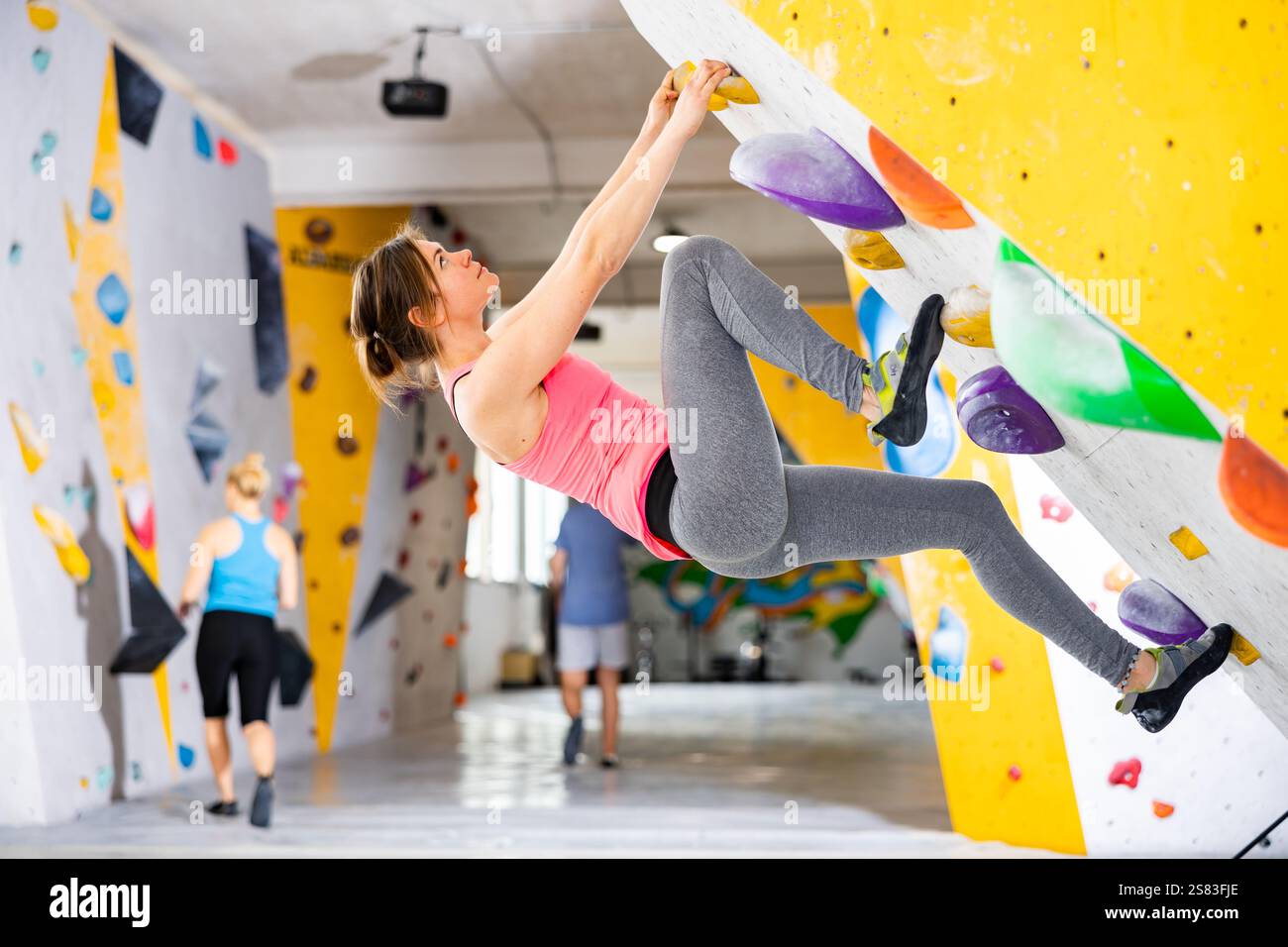 Female mountaineer climbing artificial rock wall without belay indoors ...