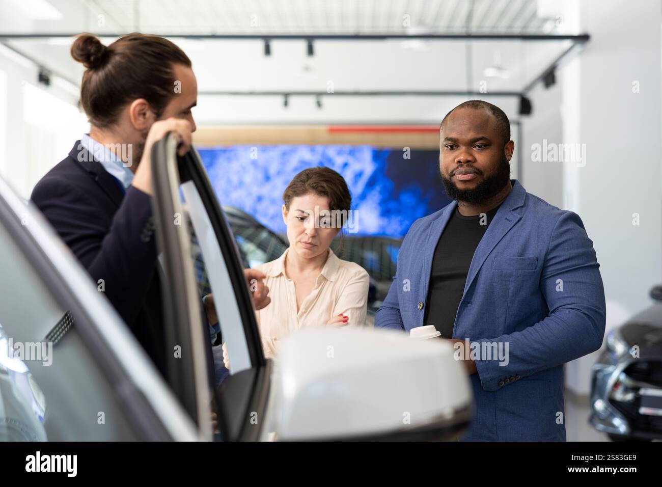 Car dealership salesman inviting customers to conduct test drives to ...