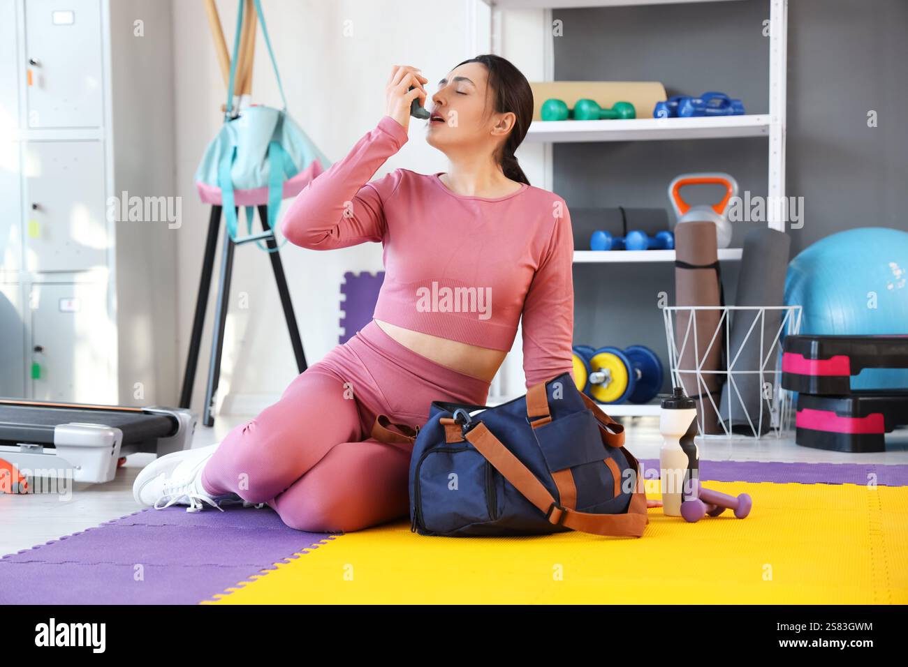 Sporty young woman using inhaler in gym Stock Photo - Alamy
