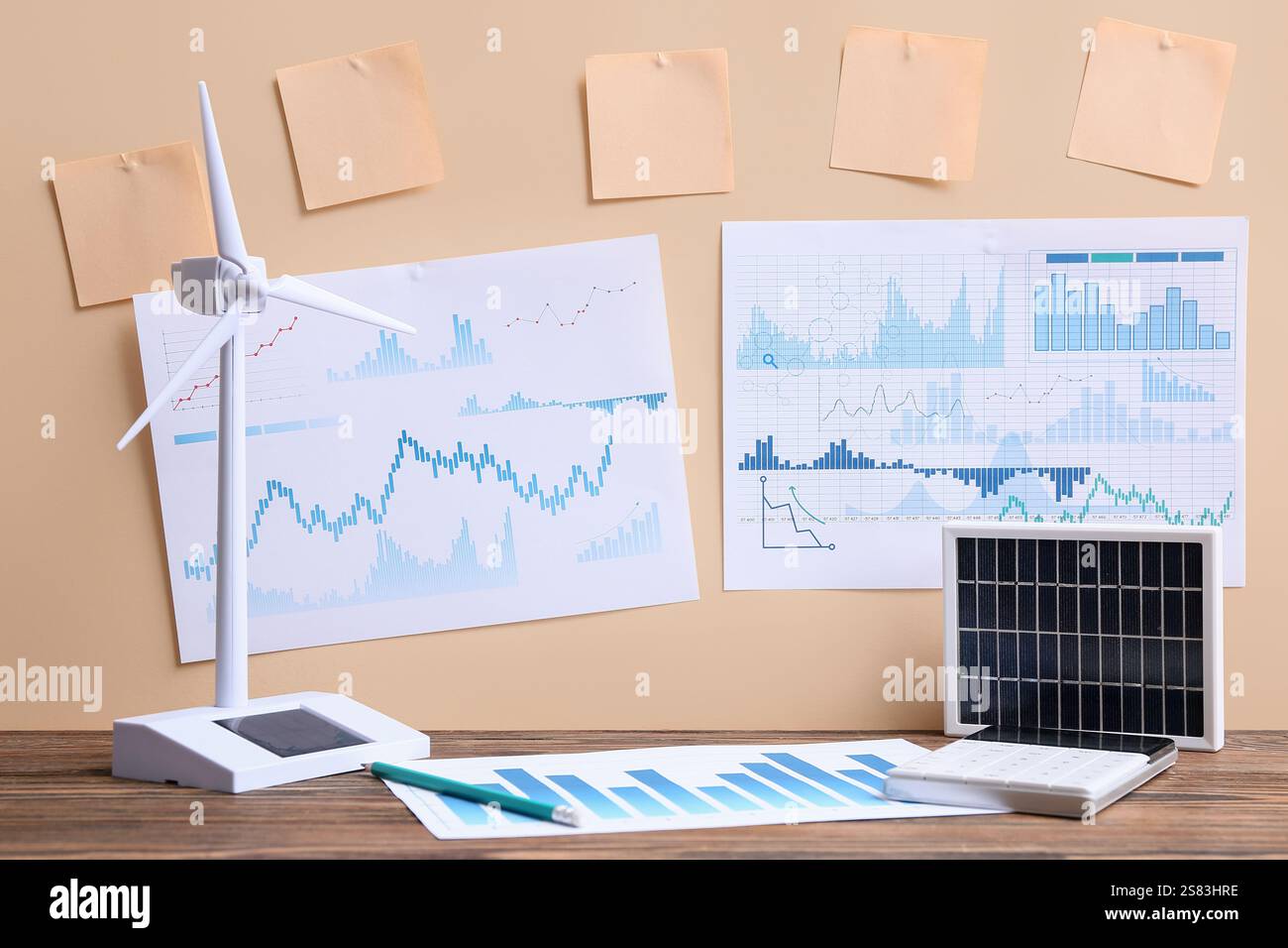 Diagrams with blank sticky notes and wind turbine model on table near ...