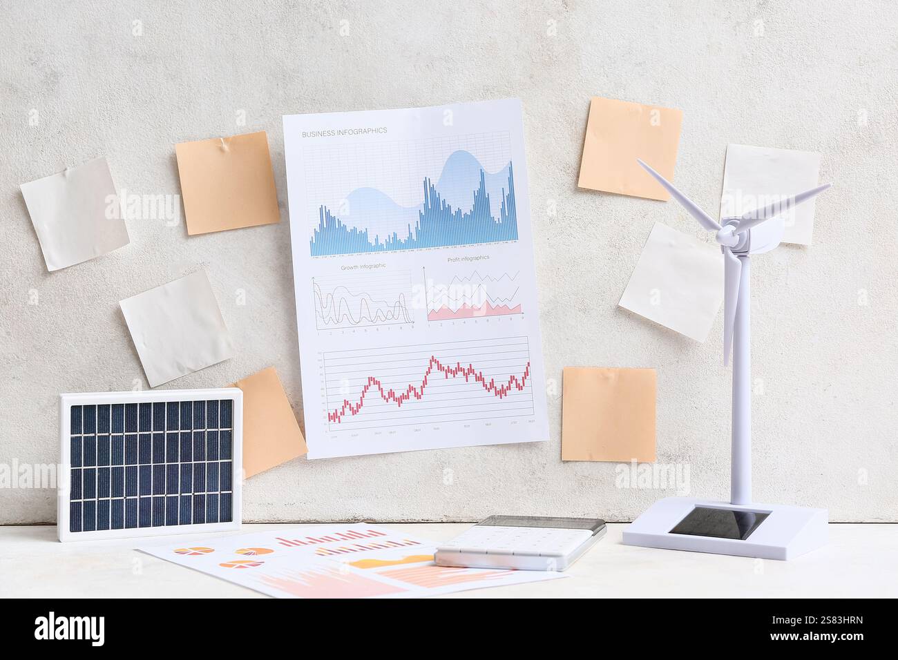 Diagrams with blank sticky notes and wind turbine model on table near ...