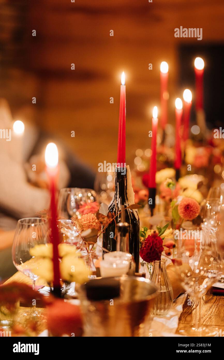 Romantic candlelit table setting with red candles, wine bottles, and ...