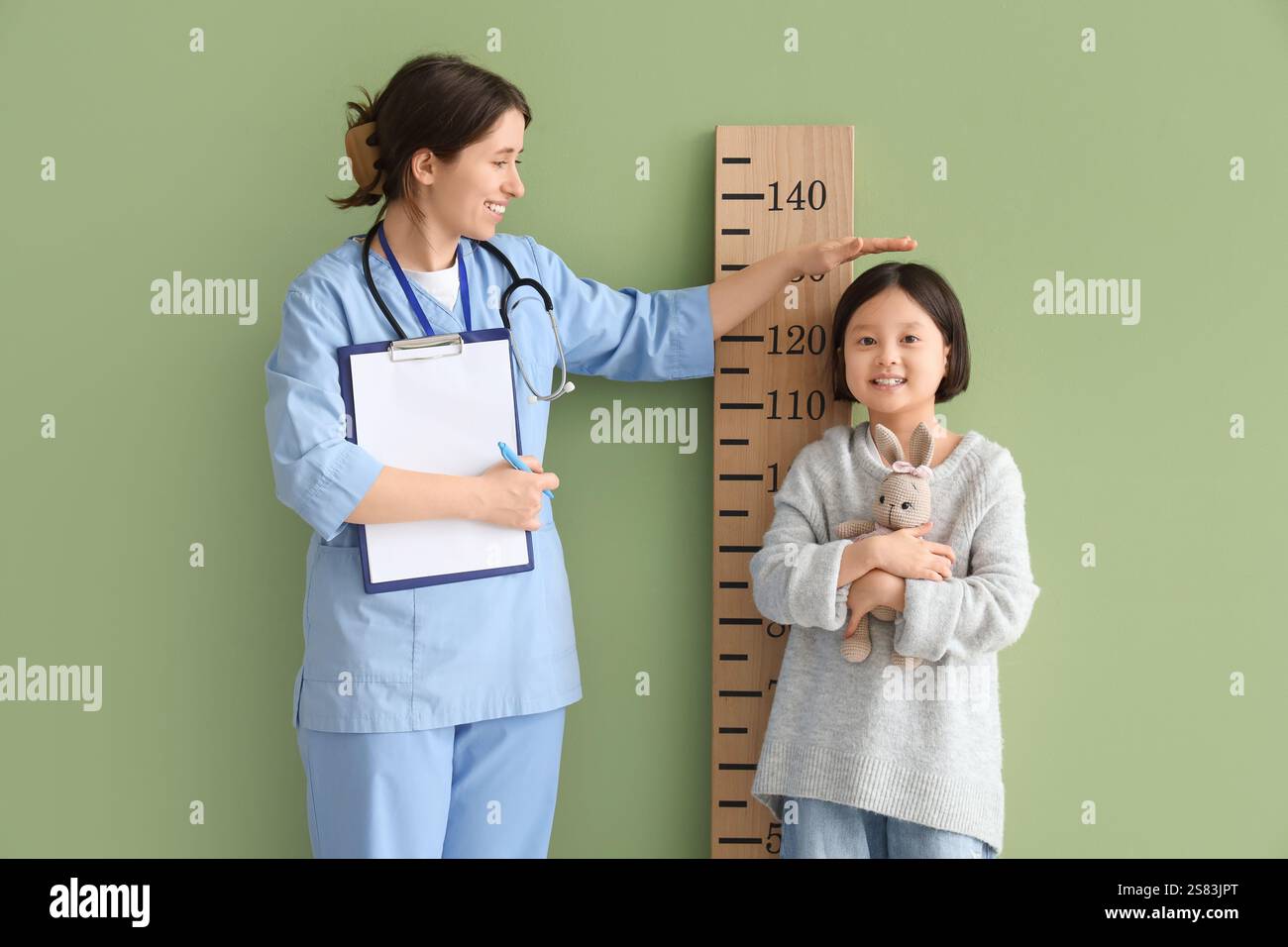 Female pediatrician and Asian girl measuring height with stadiometer ...