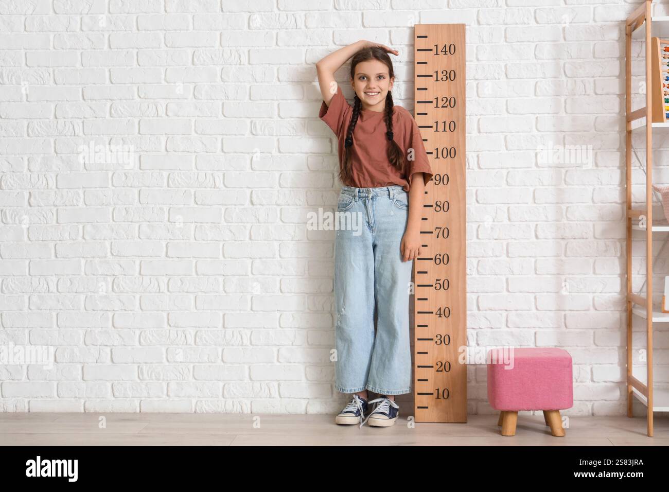 Cute girl measuring height near stadiometer at home Stock Photo - Alamy