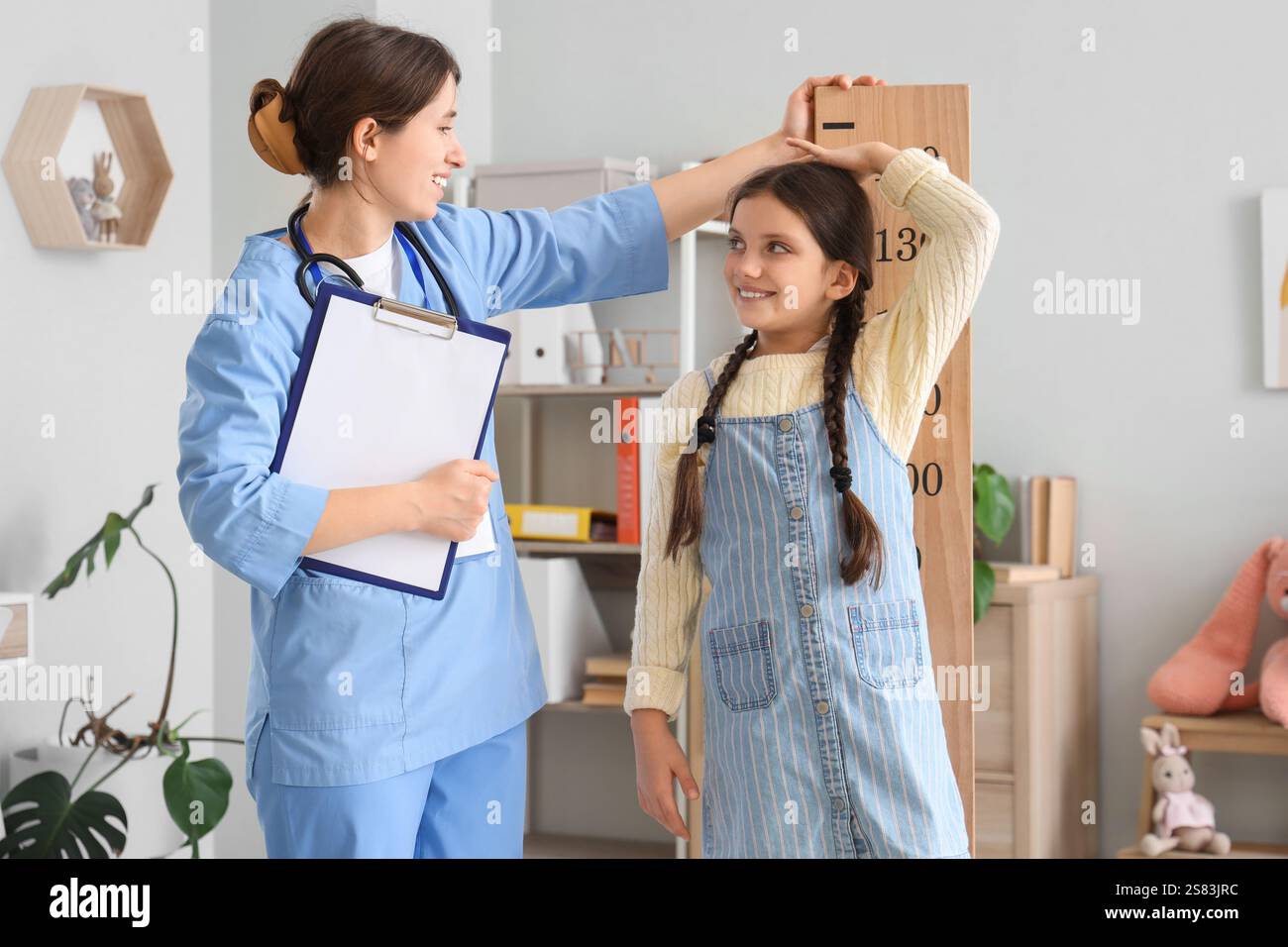 Female pediatrician with stadiometer measuring height of cute girl in ...