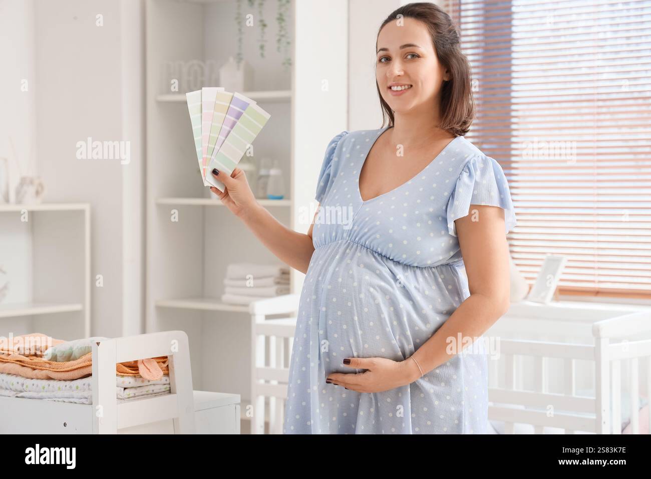 Young pregnant woman with paint color palettes in children's bedroom ...