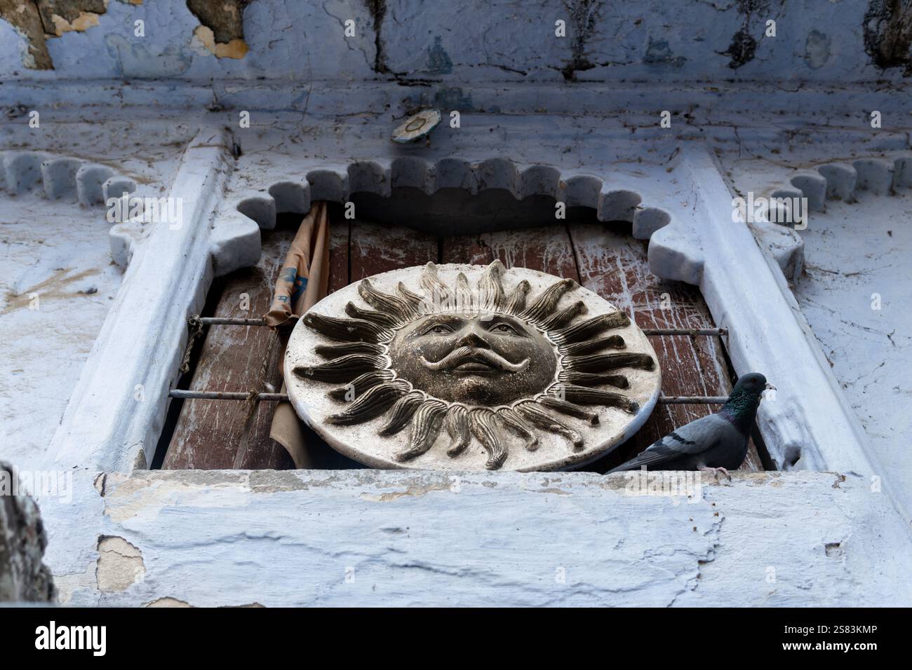 Bas-relief symbol of sun with a moustached male face on the wall of old ...