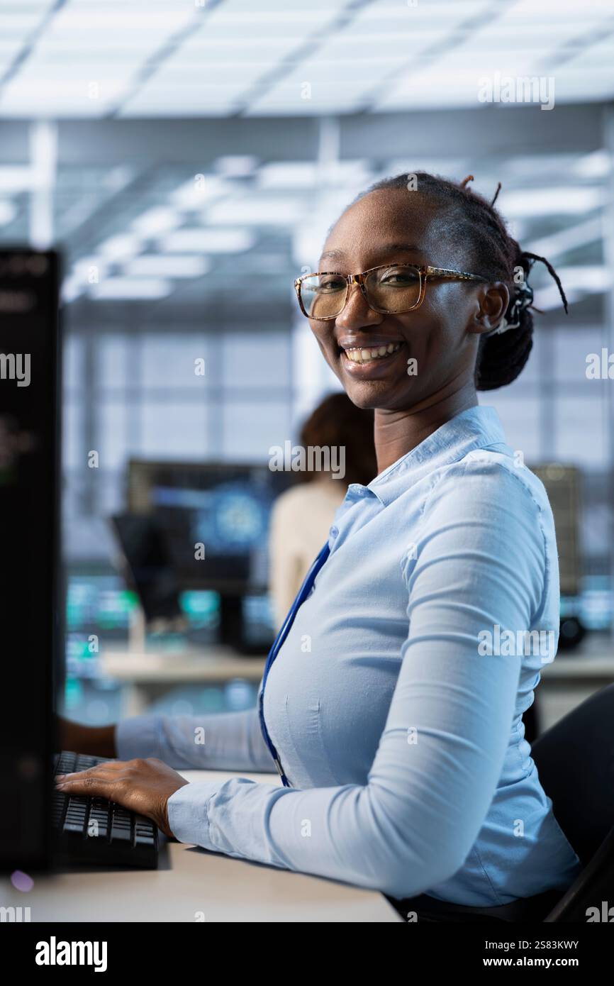 Portrait of smiling technician in data center coordinating deployment of server architecture ...