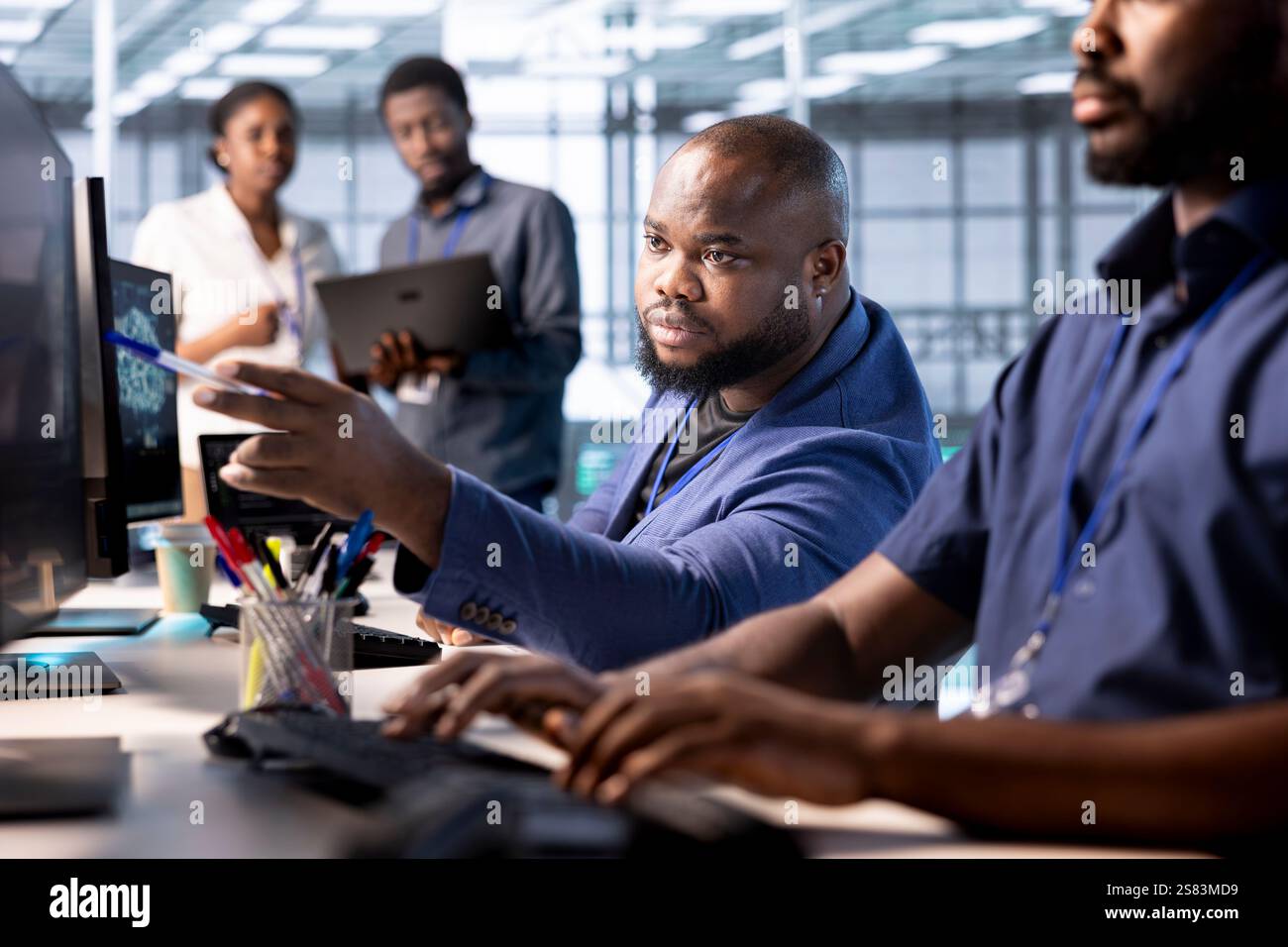 Teamworking engineers in data center using diagnostic tools and system monitoring software to ...