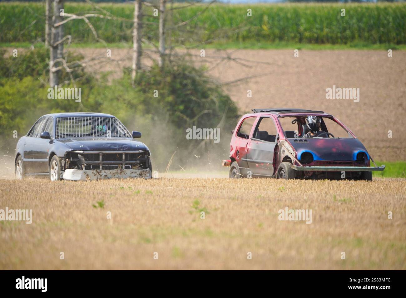 Two cars are racing on a dirt road. One of the cars is black and the ...