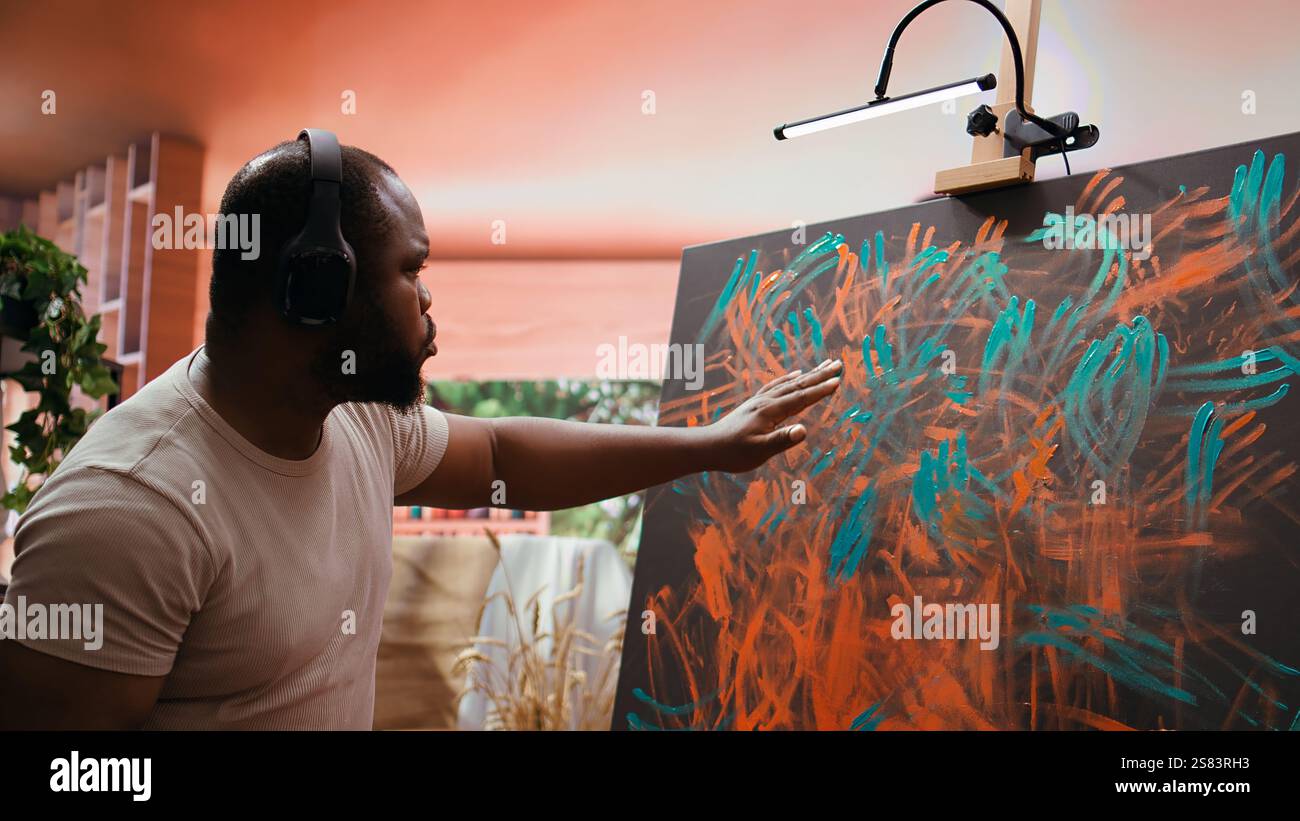 Artist listening to music and creating an abstract painting with his ...