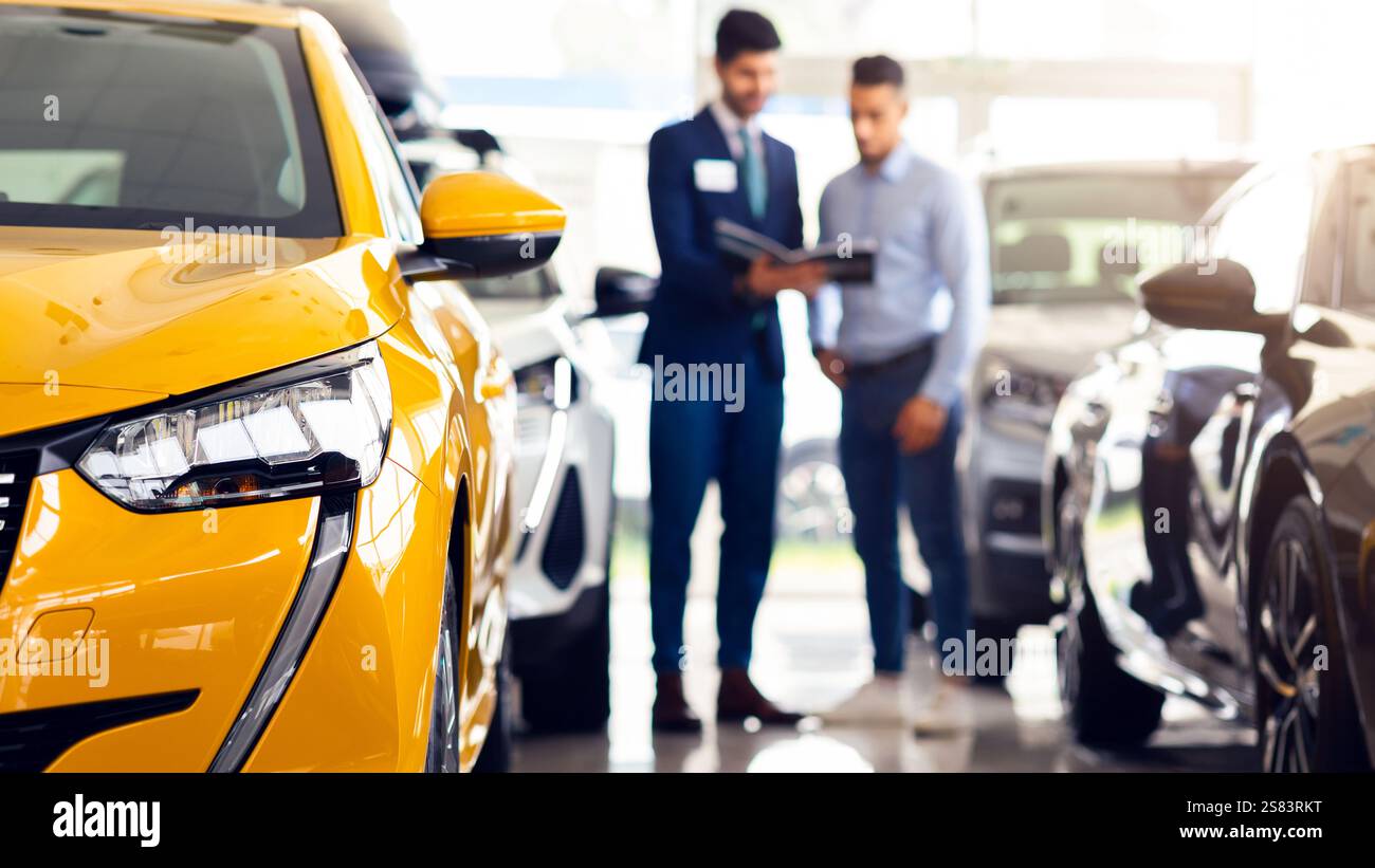 Customer standing among cars, having conversation with sales assistant ...
