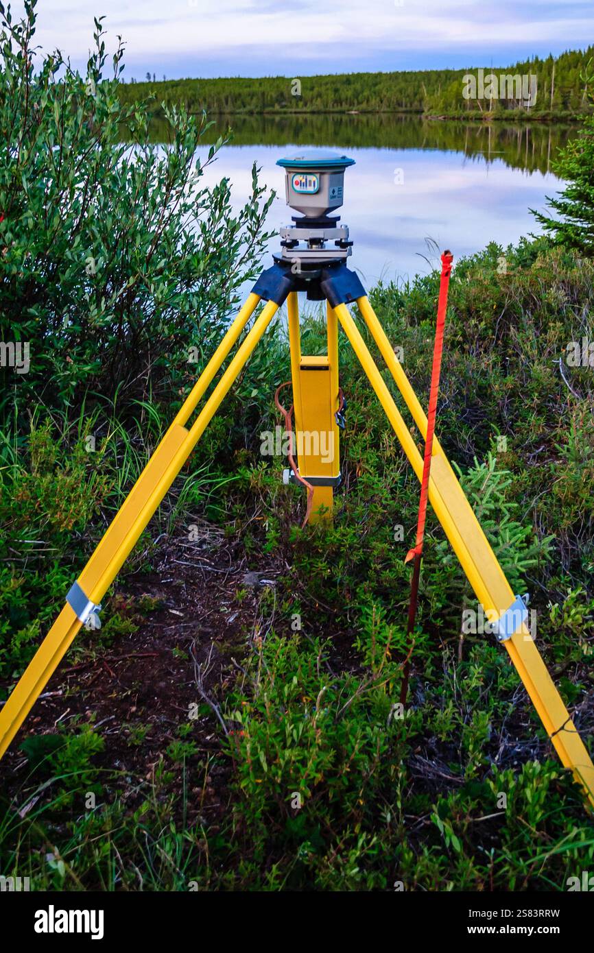 A yellow tripod is set up in a field next to a body of water. The ...