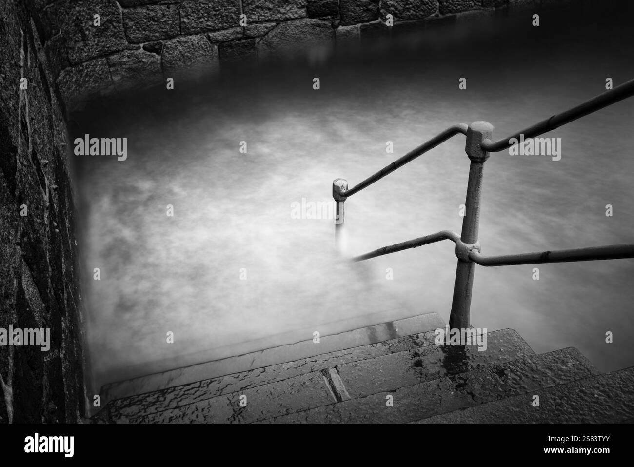 Stone steps and railings leading into blurry sea at tidal seawater ...