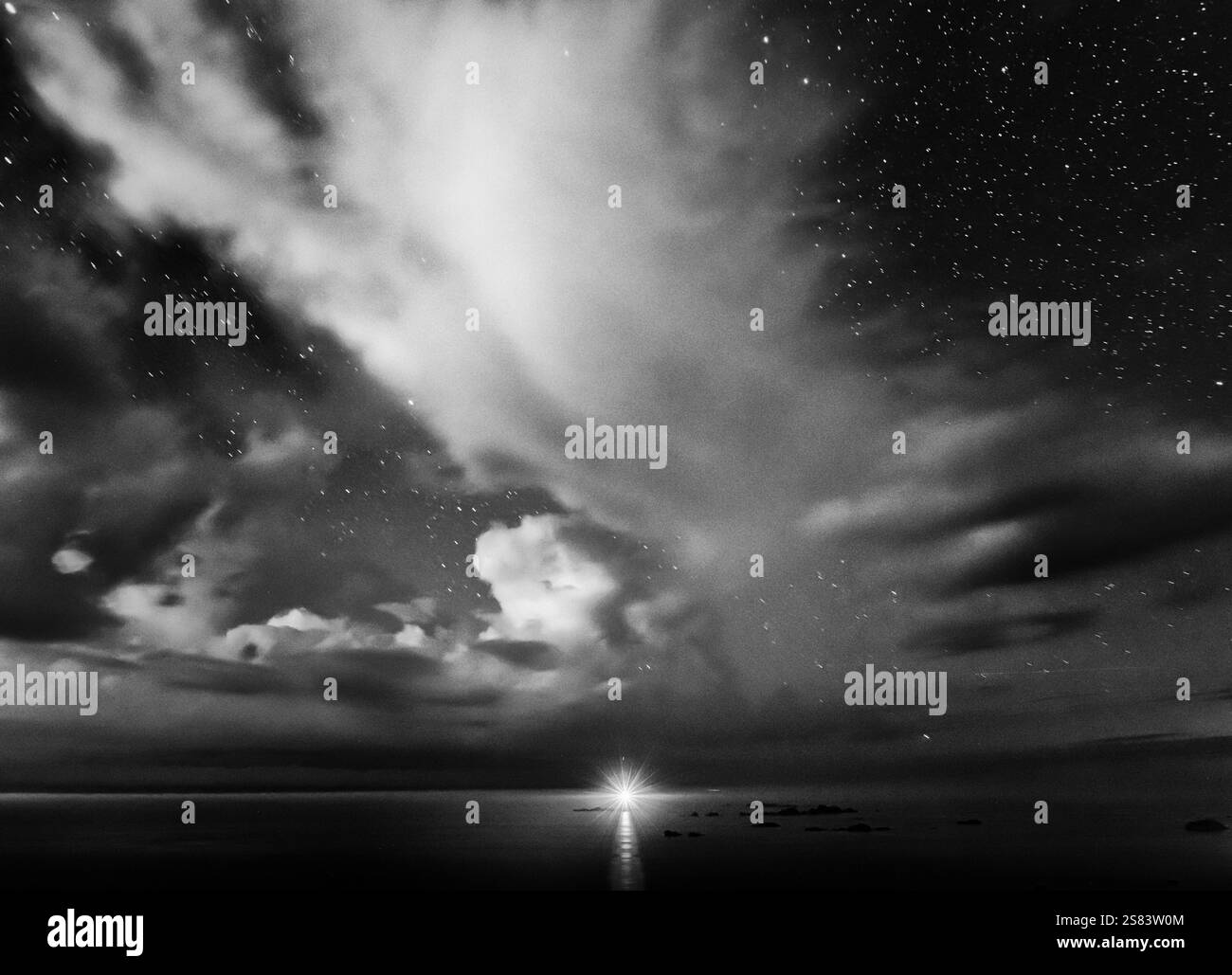 Night time sea and cloudscape with distant lighthouse. Hanois ...