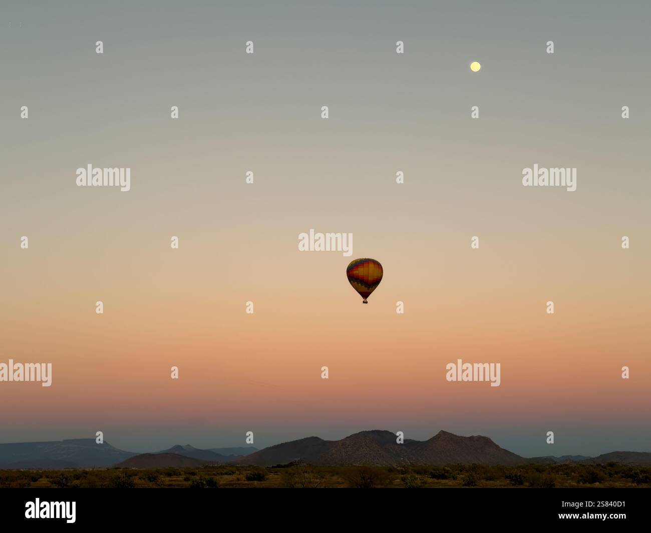 Single hot air balloon flying low over hills in the desert of Phoenix ...