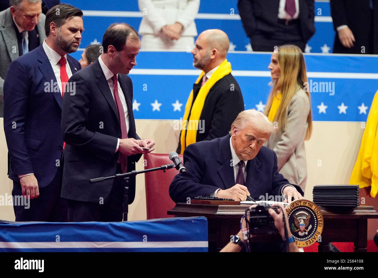 President Donald Trump signs executive orders on stage at an indoor ...