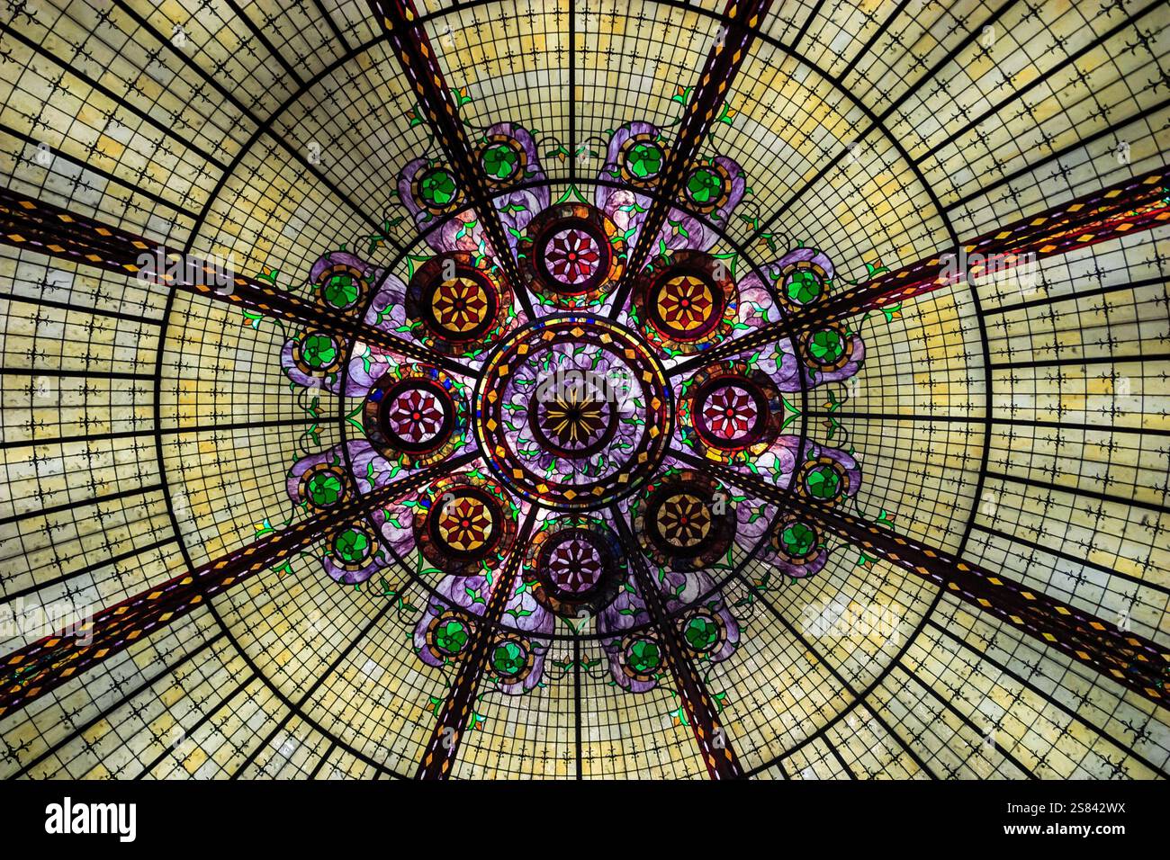 A stained glass window with a circular design. The window is filled with many different colored ...