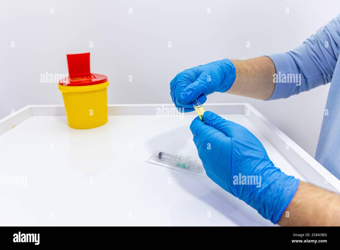 On a white background, hands in blue latex gloves remove and break an ...