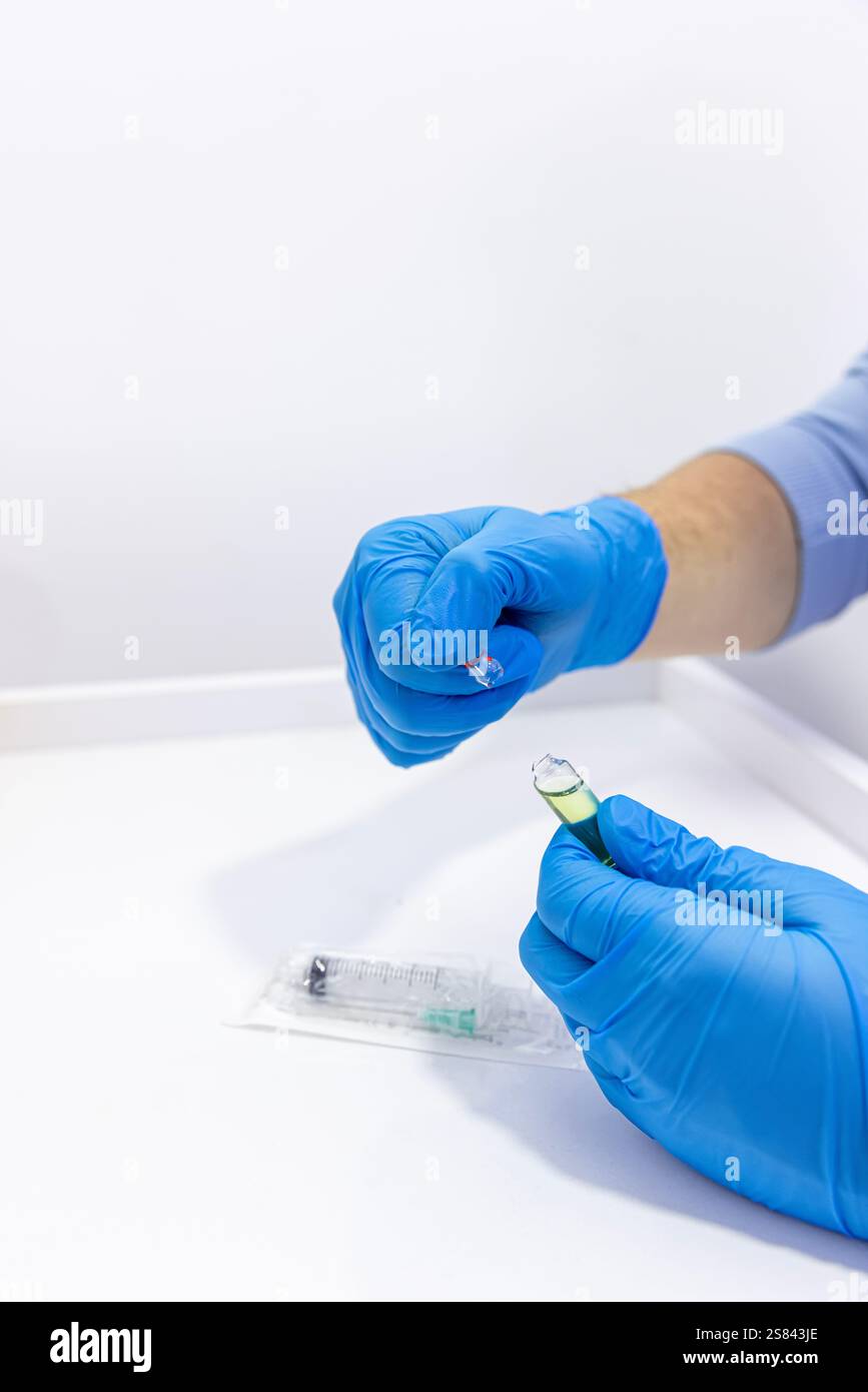 On a white background, hands in blue latex gloves remove and break an ...