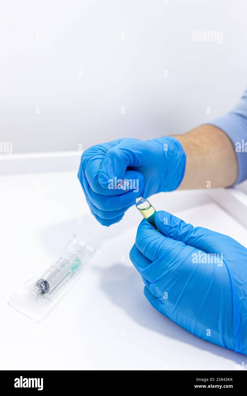 On a white background, hands in blue latex gloves remove and break an ...