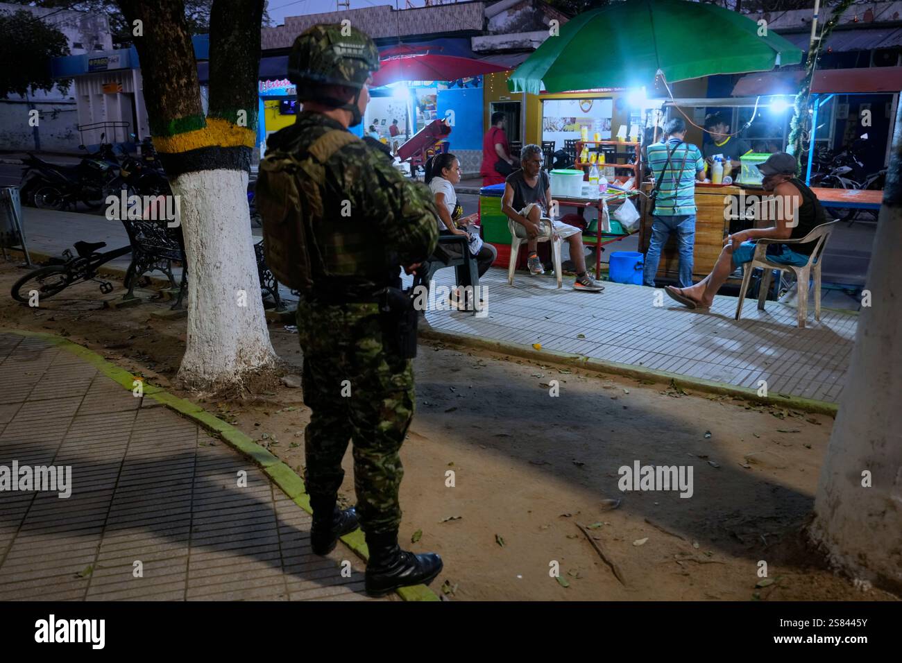 Residents gather under the watch of a soldier in Tibu, Colombia, on ...