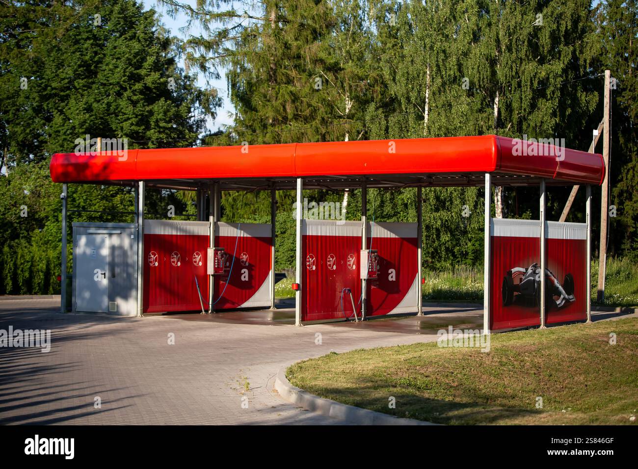 A car wash station with a bright red roof, multiple washing bays, and ...