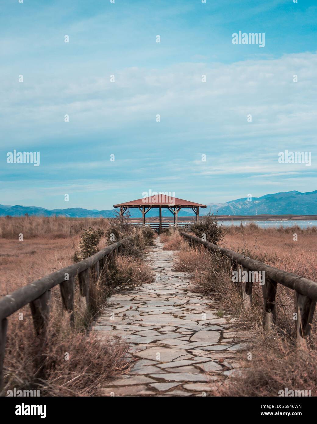 A stone pathway with wooden railings leads to a red roofed gazebo near ...