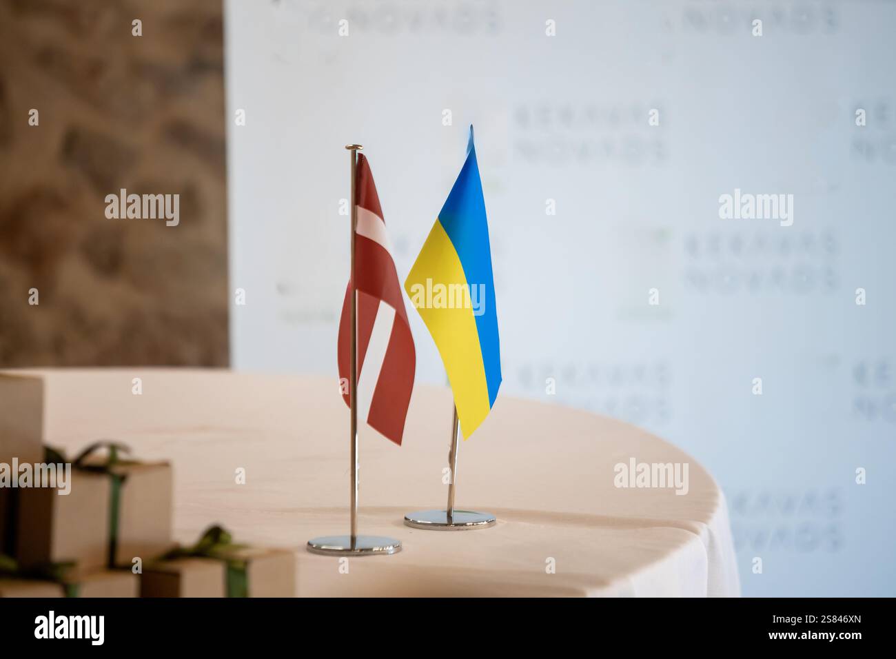 Two small table flags of Latvia and Ukraine on a round table with a ...