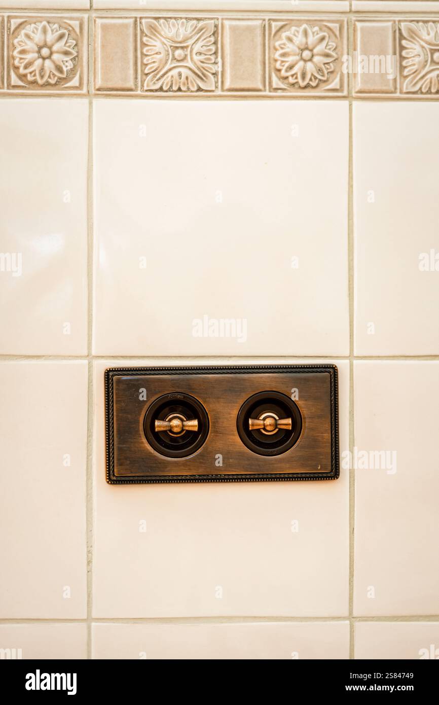 Beige ceramic tiles with a brass fixture featuring two knobs and floral ...