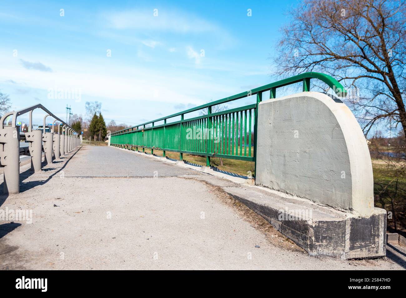 A pedestrian bridge with green metal railings and a concrete base, set ...