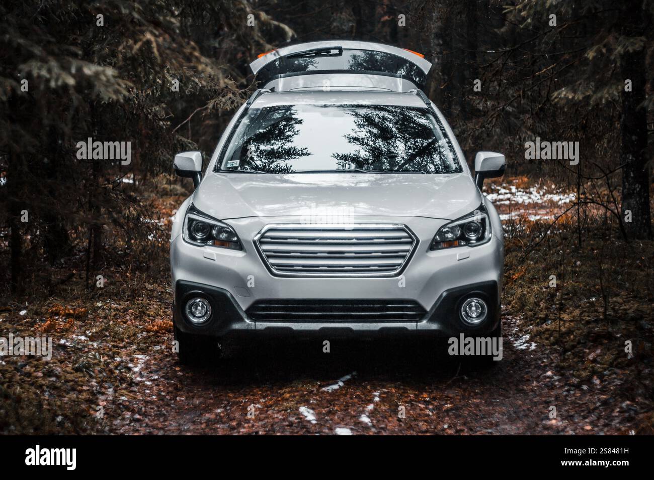 A white SUV with its rear hatch open sits on a narrow dirt path ...