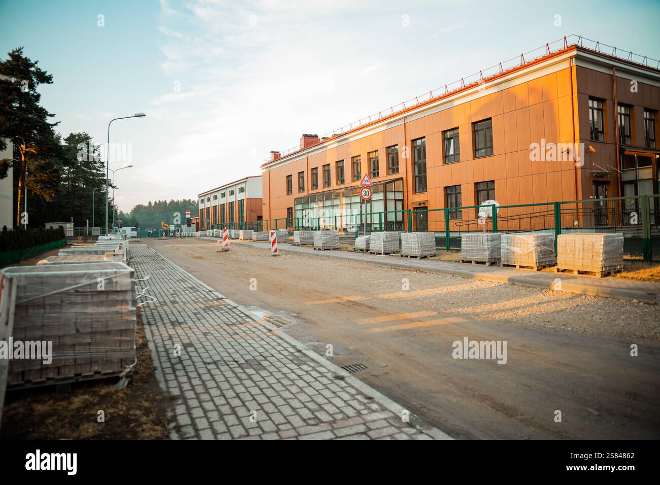 Partially paved road with construction materials near a modern two ...