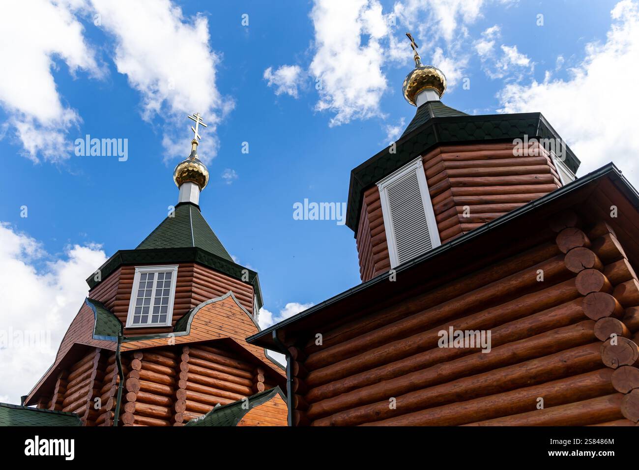 Two wooden church towers with green roofs and golden domes, featuring ...