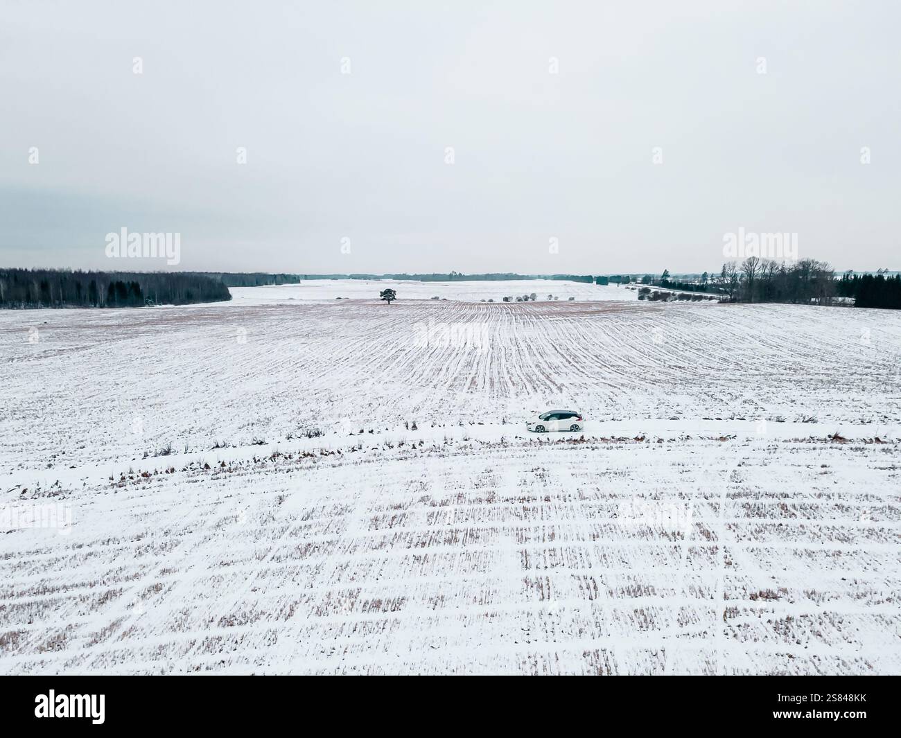 A vast snow covered field with faint crop rows, a parked vehicle near ...
