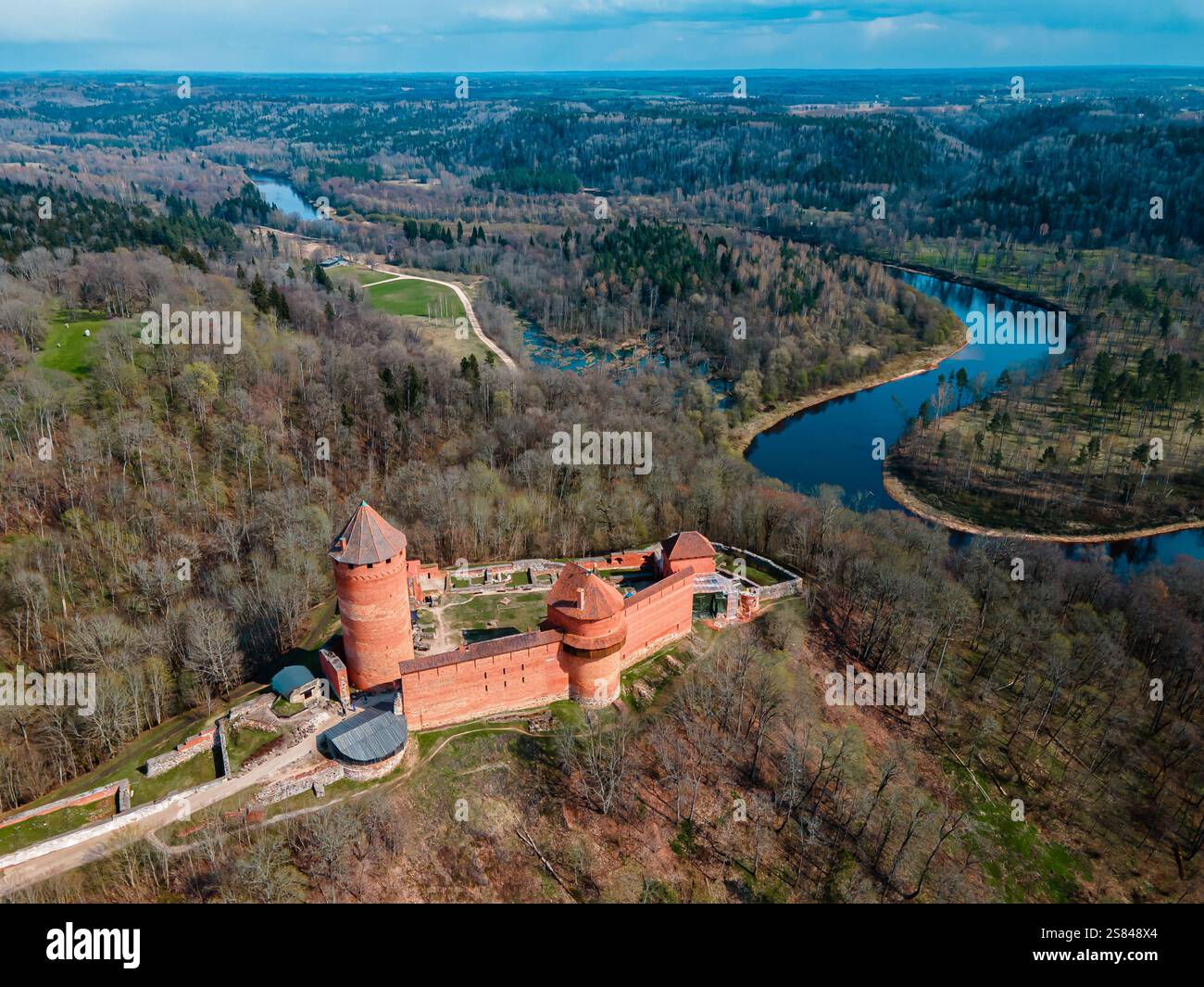 Turaida Castle's red brick towers rise above a forested area with the ...