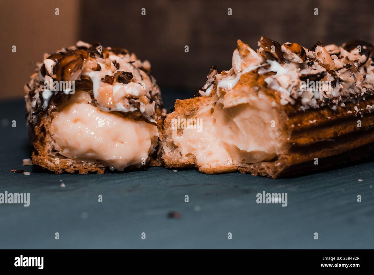 A detailed view of a split eclair with creamy custard filling, topped ...