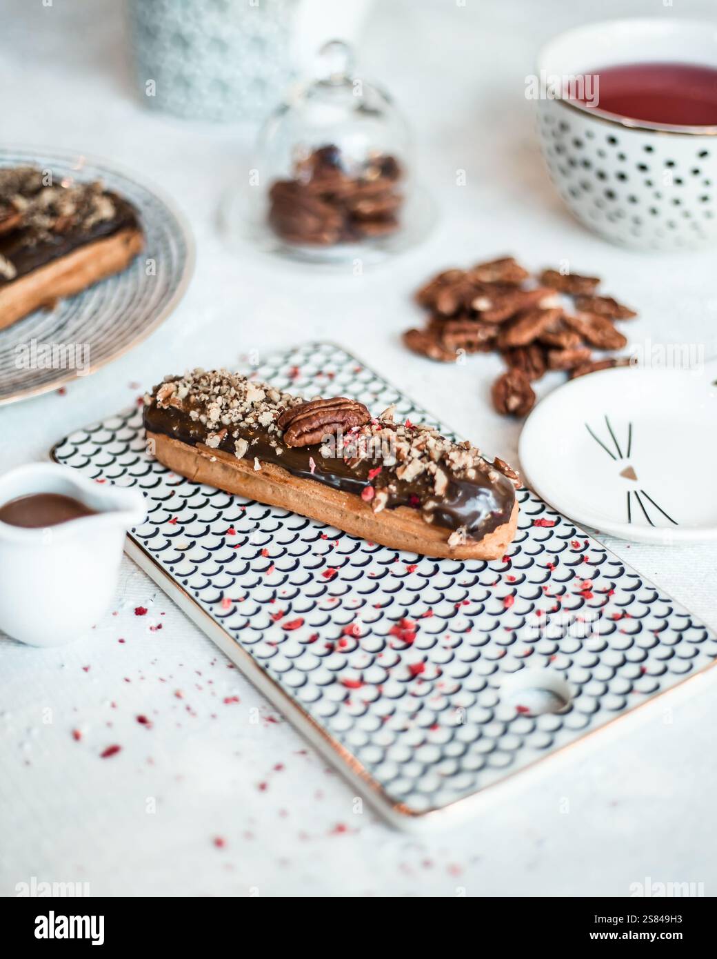 Chocolate eclair topped with nuts and pecan on a fish scale board ...