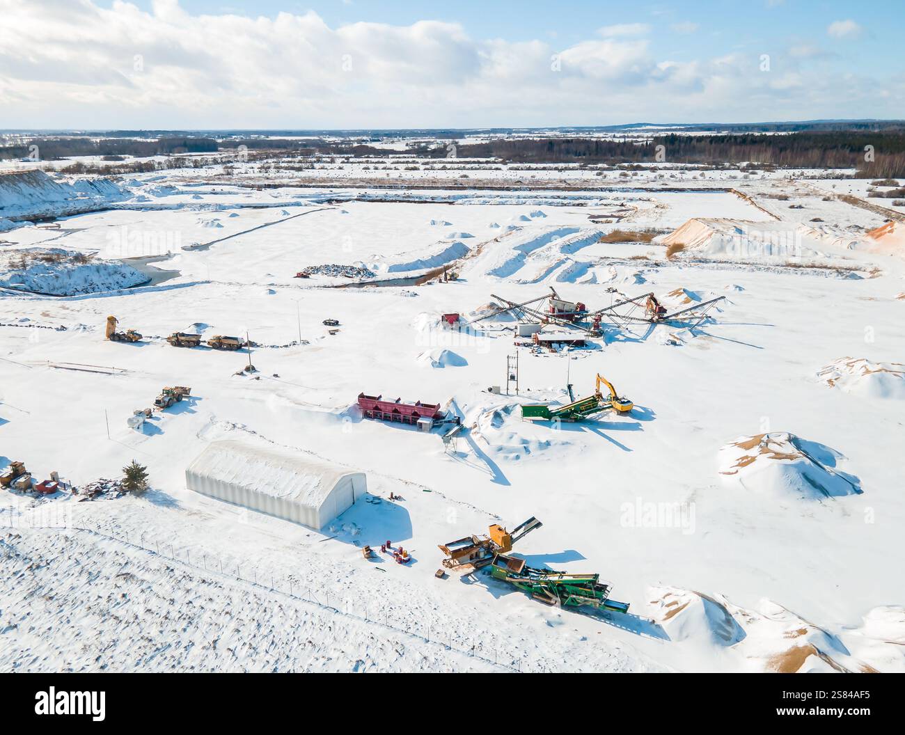 An expansive snow covered quarry featuring conveyor belts, excavators ...