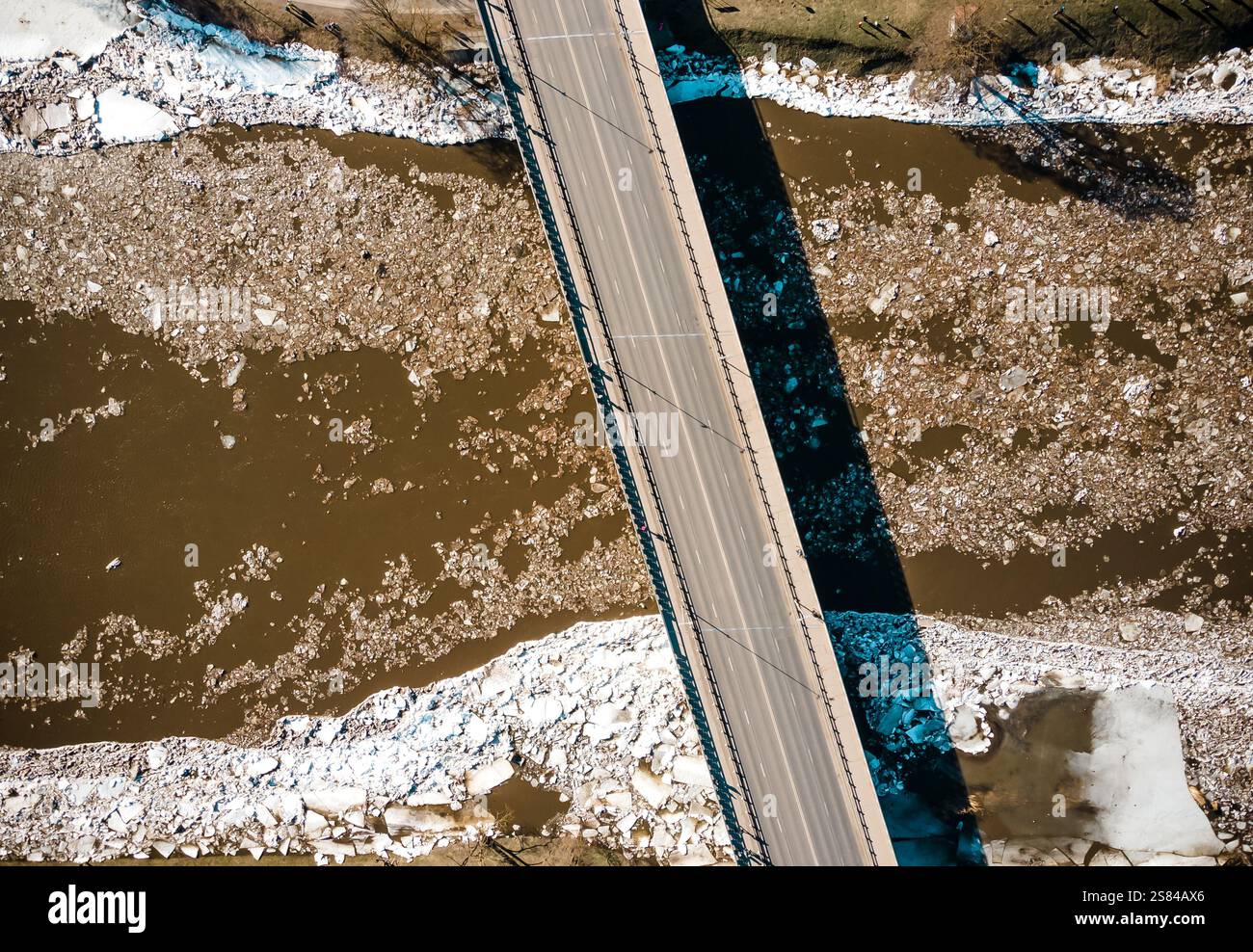 An aerial perspective of a straight bridge crossing a muddy, partially ...