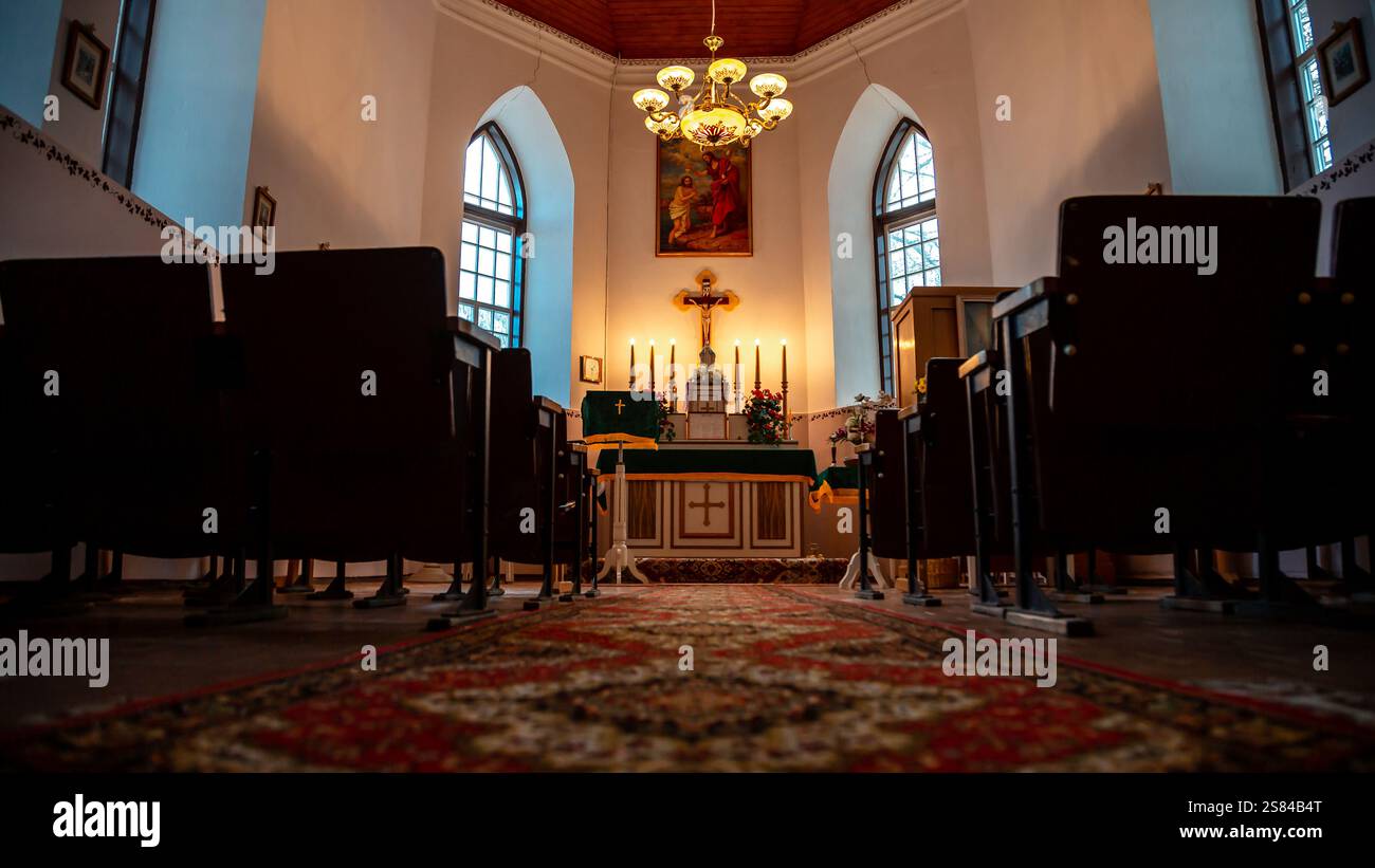 A small church interior featuring a central altar with a cross, candles ...