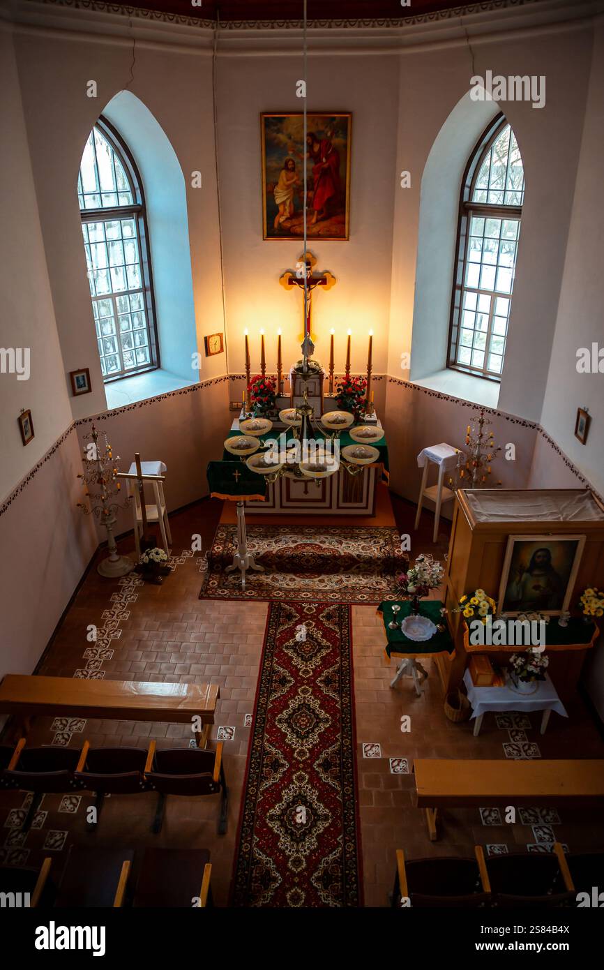 A small church interior featuring a central altar with candles, green ...