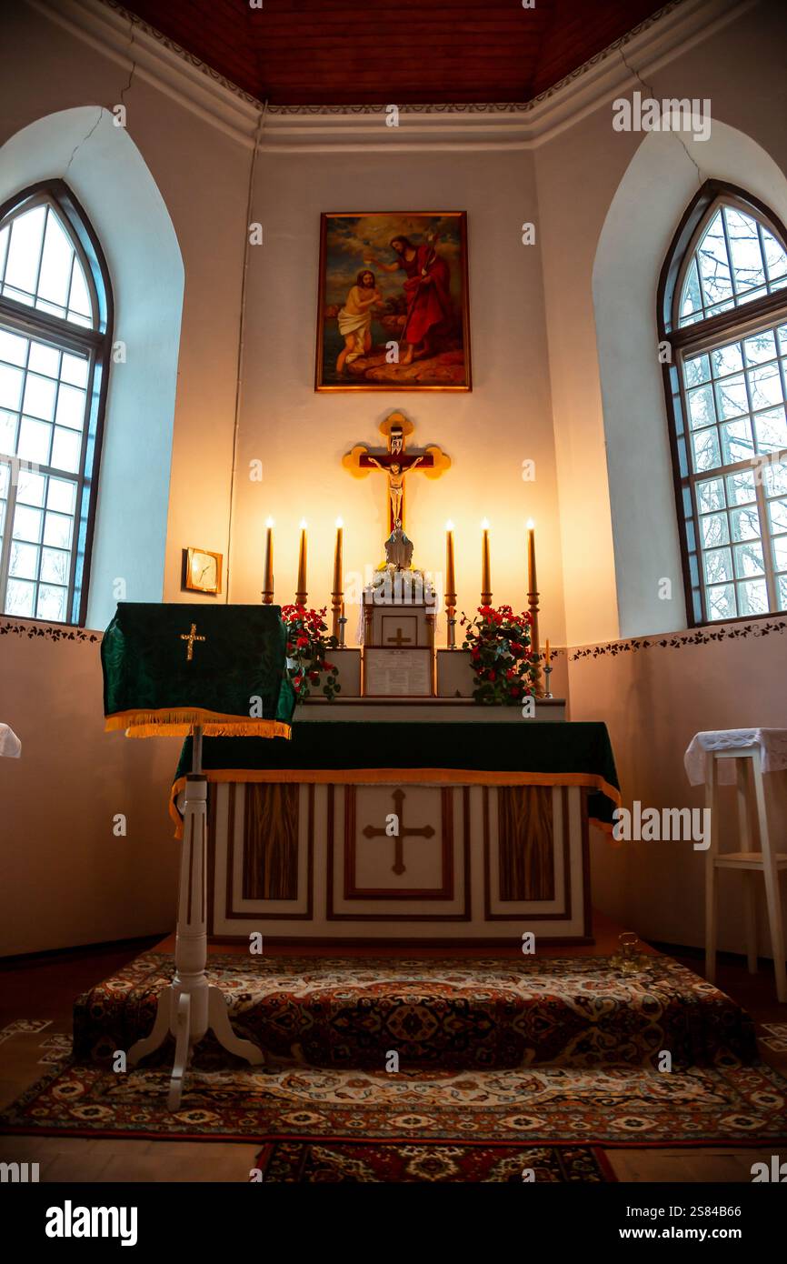 A church interior featuring an altar with a green cloth, gold cross, crucifix, lit candles ...